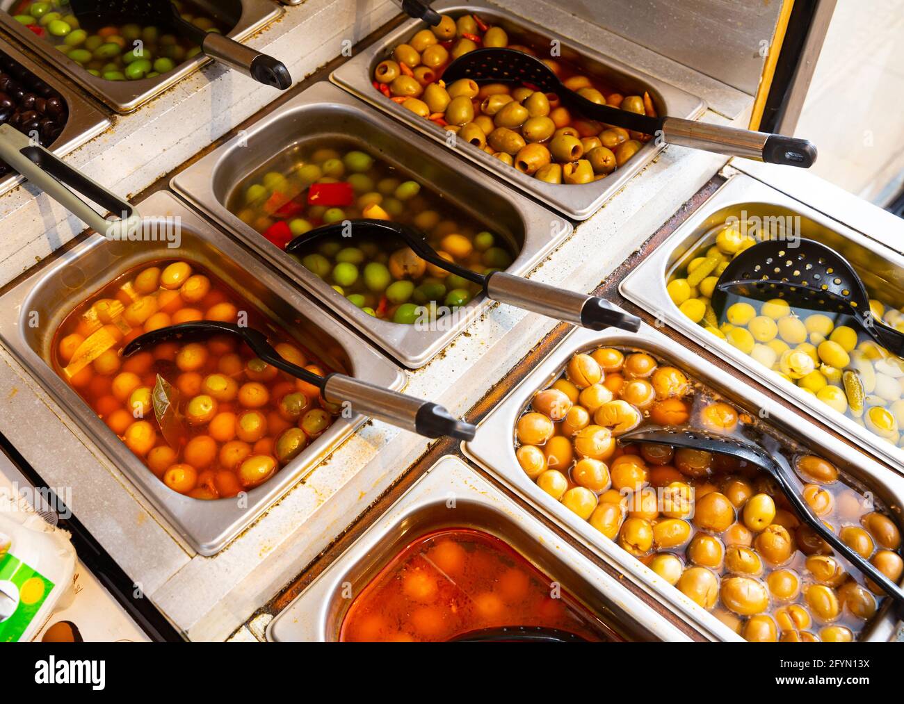 Marinated olives cooked to different recipes in metal containers for ...