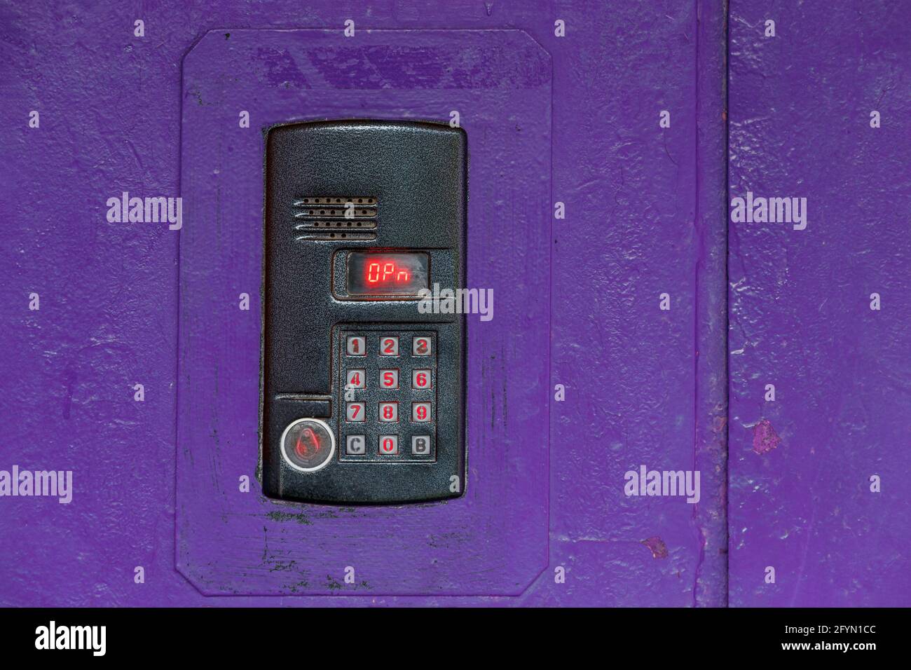 An intercom on purple painted red steel surface with a keypad, digital ...