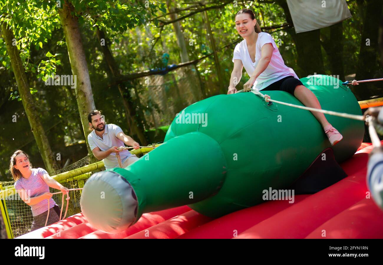 Happy adults having fun in outdoor amusement park, pulling ropes of ...