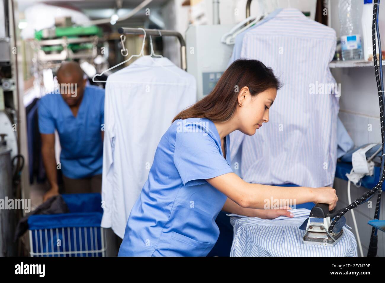 Female laundry worker ironing clean clothes in dry cleaning salon Stock ...