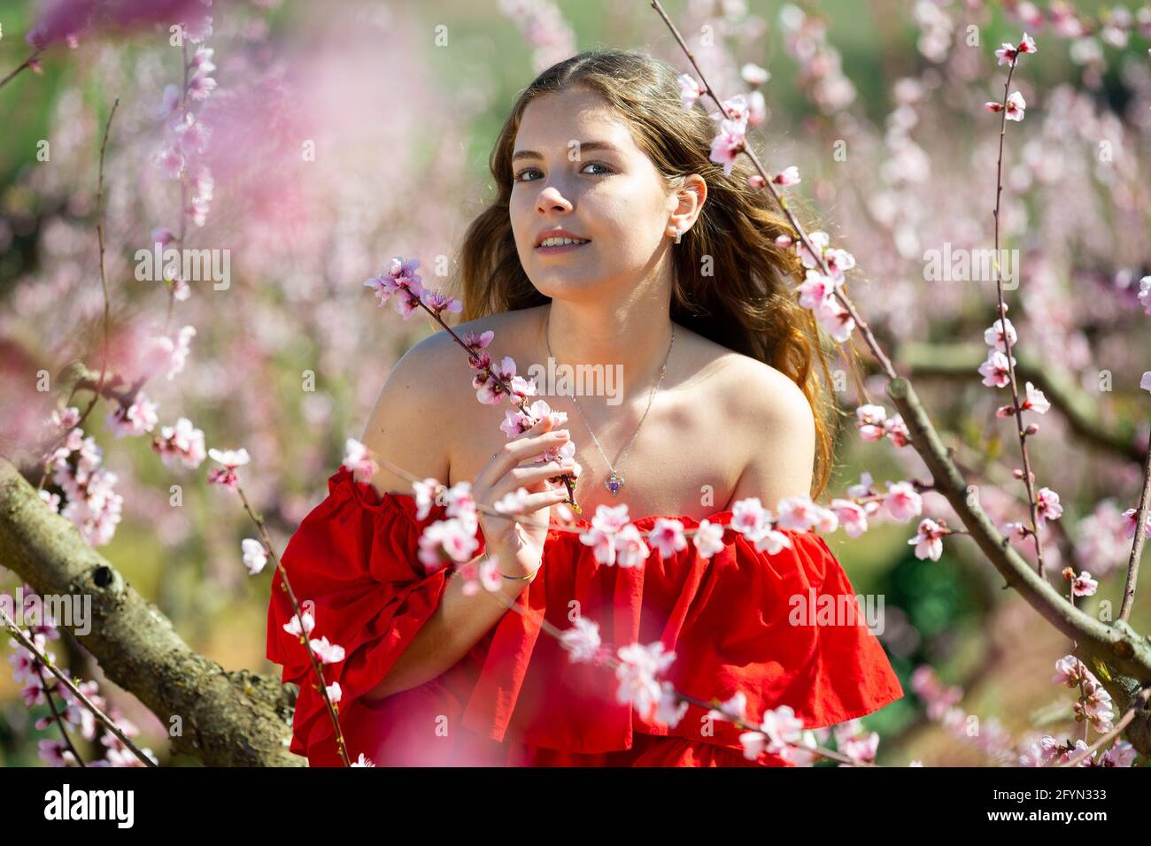 Beautiful smiling young american woman posing in park with blooming ...