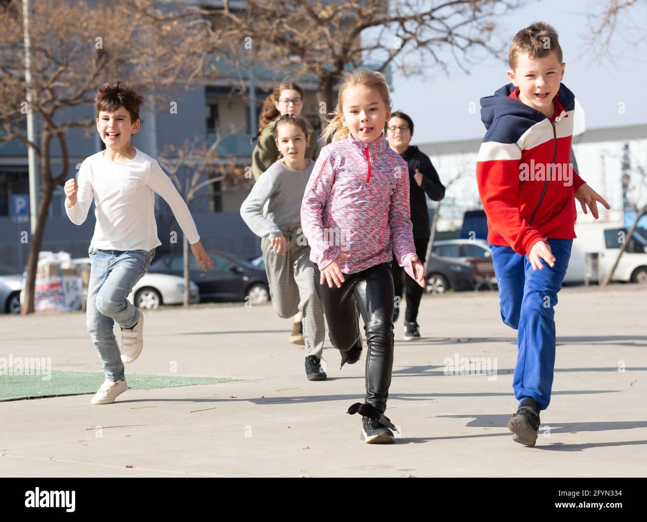 Large group of playful children running together at urban landscape ...