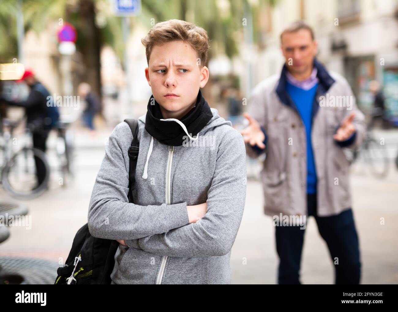 Portrait of upset teenage boy scolded by father outdoors in autumn day ...