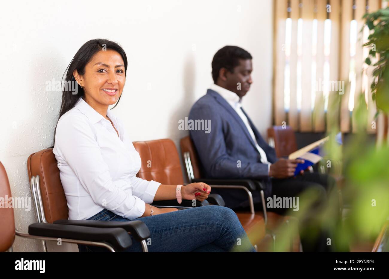 Smiling confident Hispanic woman waiting for job interview, sitting on ...