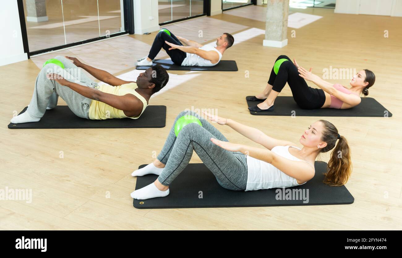 International group of sporty young adults performing set of pilates ...