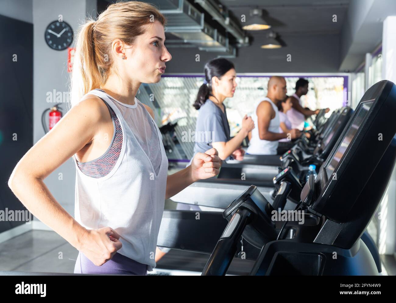 Slender athletic positive european girls running on treadmill in ...