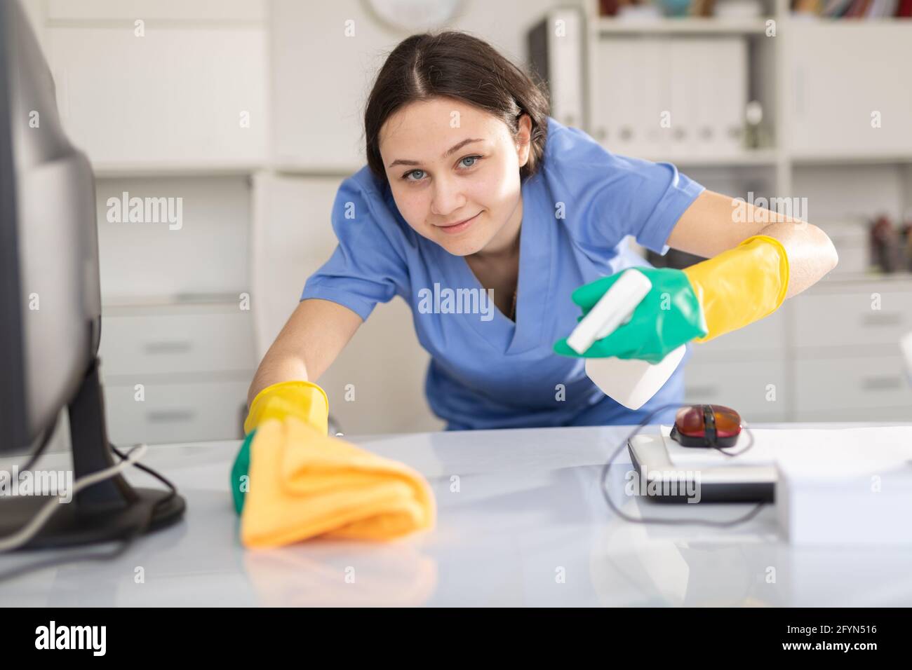 Cleaning company employee wipes dust from table in office Stock Photo ...