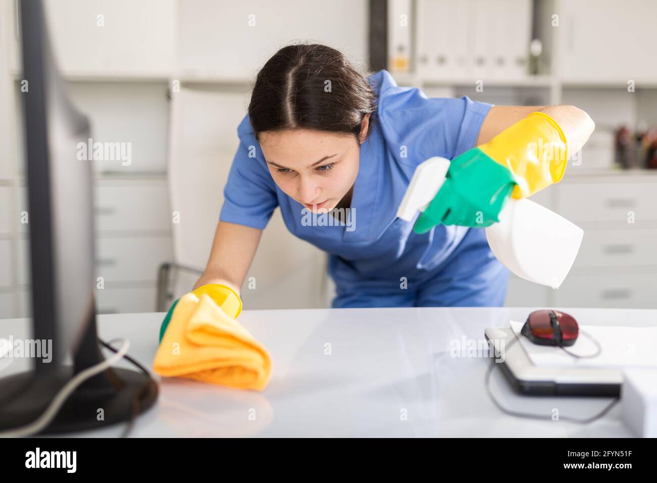 Cleaning company employee wipes dust from table in office Stock Photo ...