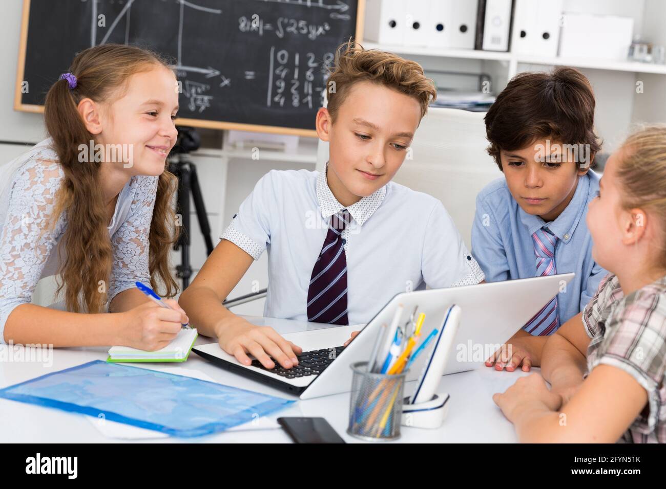 Boys and girls pupils talking near the notebook in the math class Stock ...