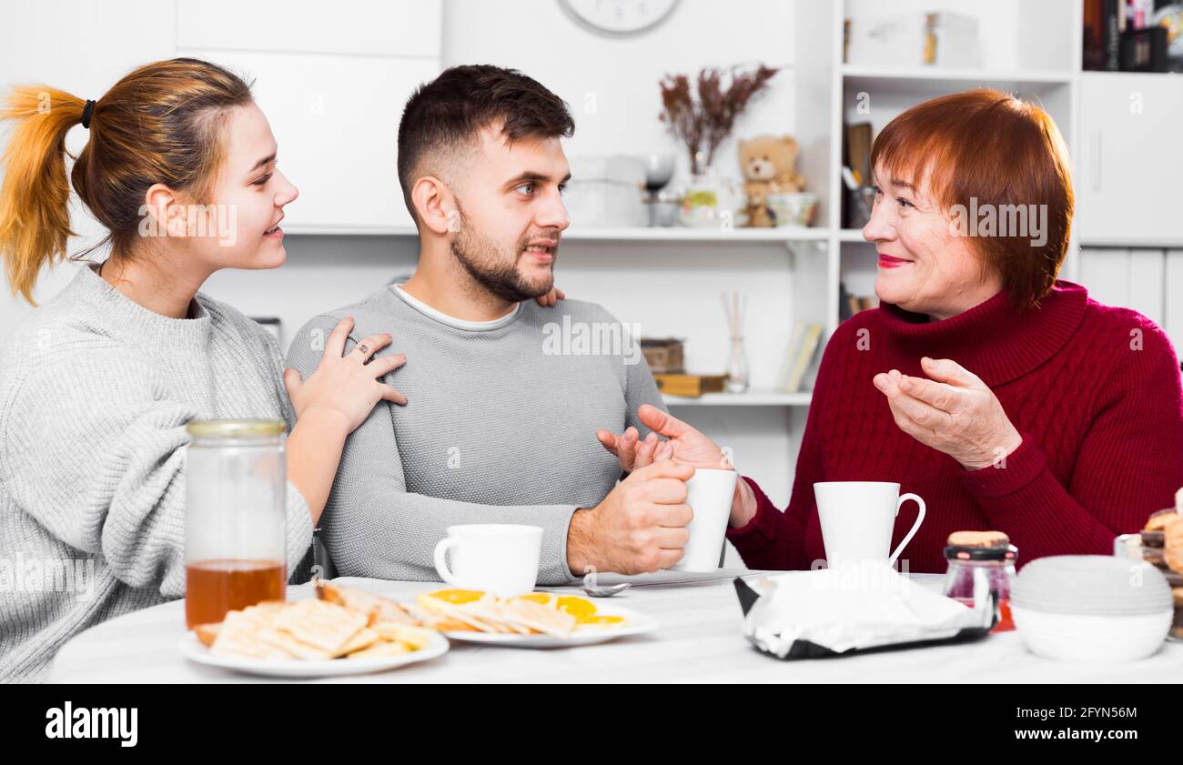 Portrait of happy family enjoying conversation over cup of coffee at ...