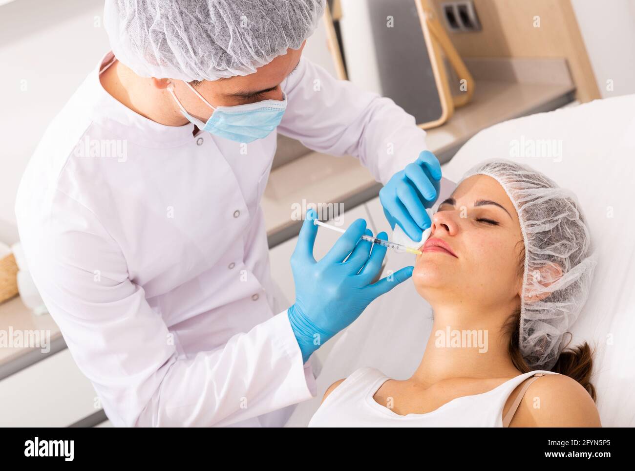Young woman patient of beautician receiving rejuvenating facial ...