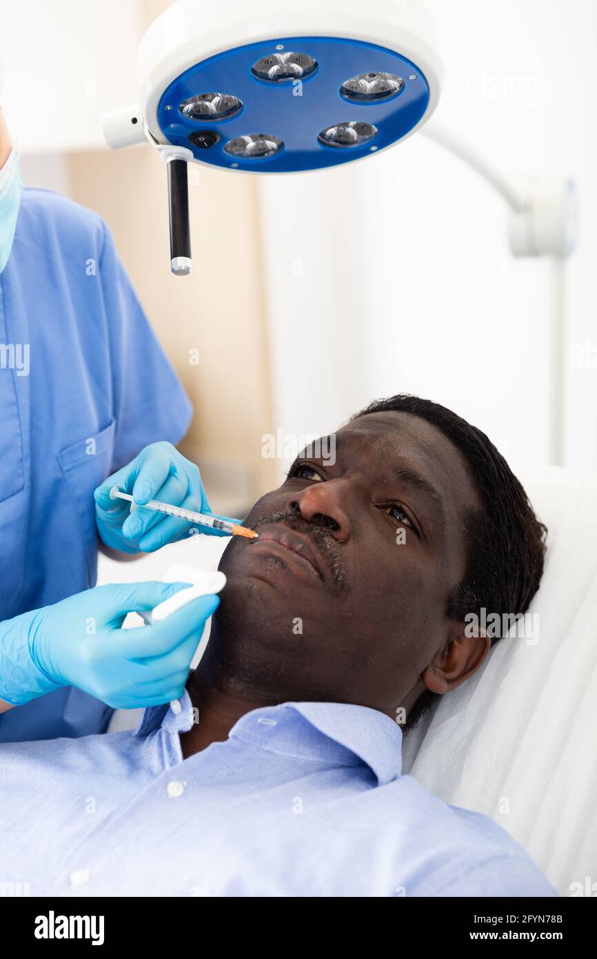 African male patient getting beauty injection for lips at aesthetic ...