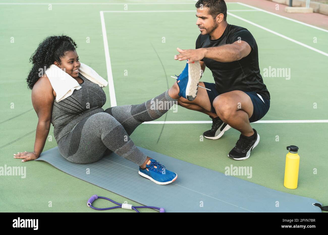 Personal trainer working with curvy woman explaining her the exercises ...