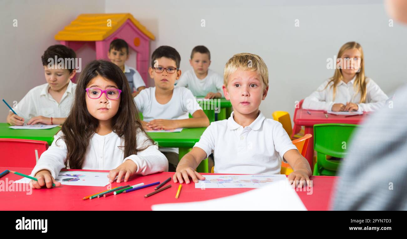 Portrait of surprised little pupils at lesson in classroom at ...