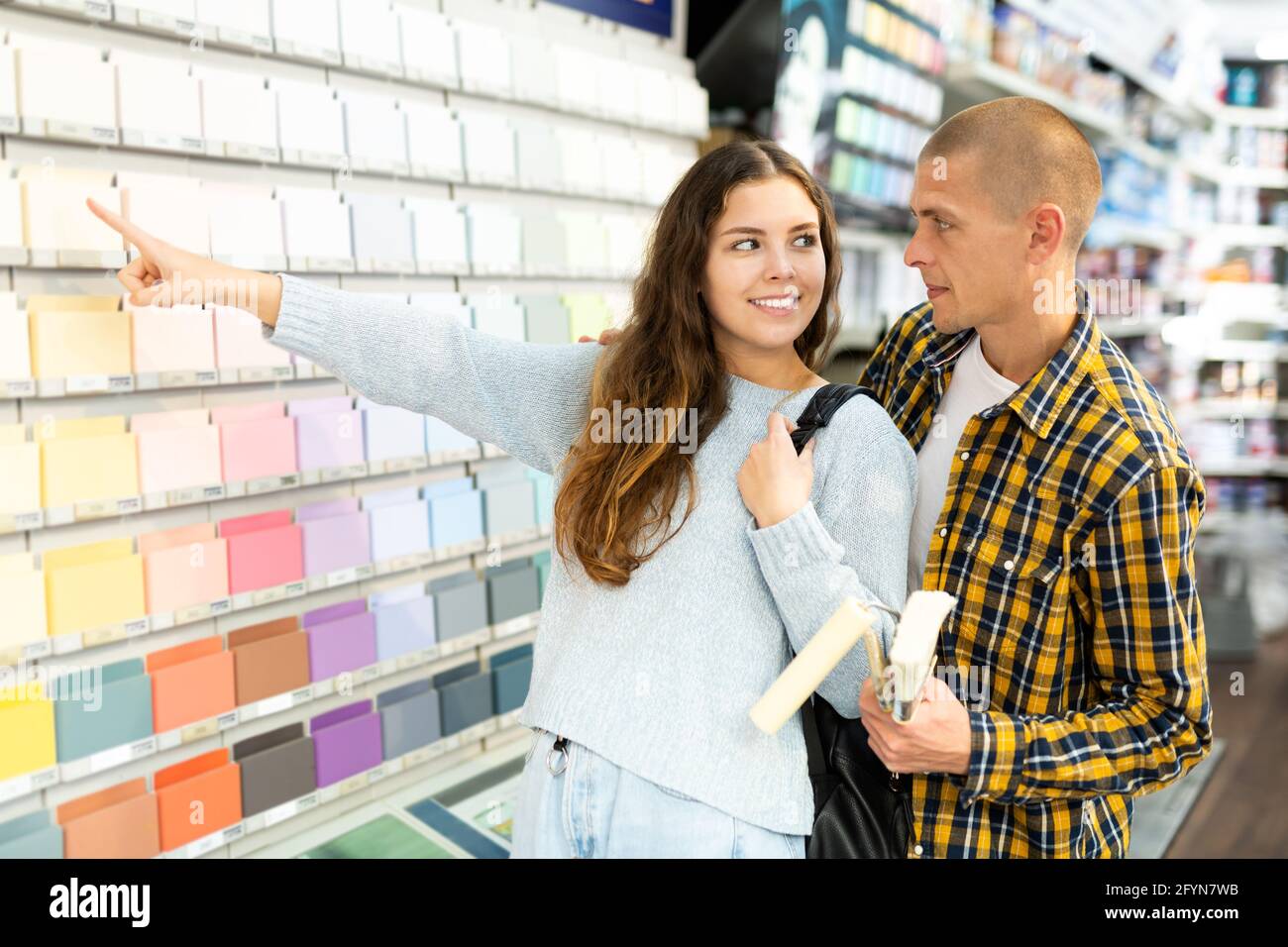 Couple of positive customers choosing together paint color for ...