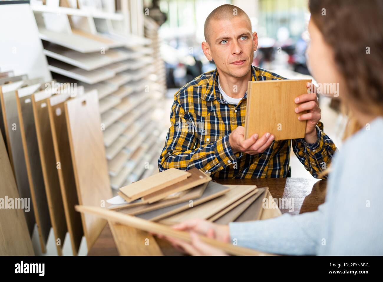 Experienced salesman offering laminated flooring to customer in shop of ...