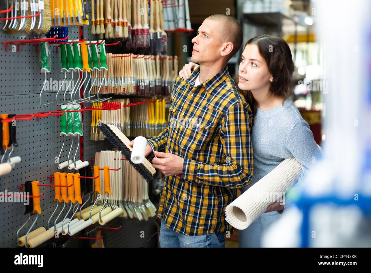 Happy married couple are choosing different tools at the hardware store ...