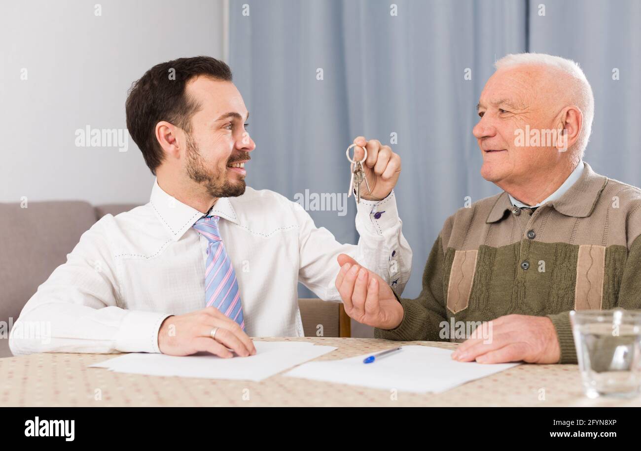 Old smiling man signing realty papers at home Stock Photo - Alamy