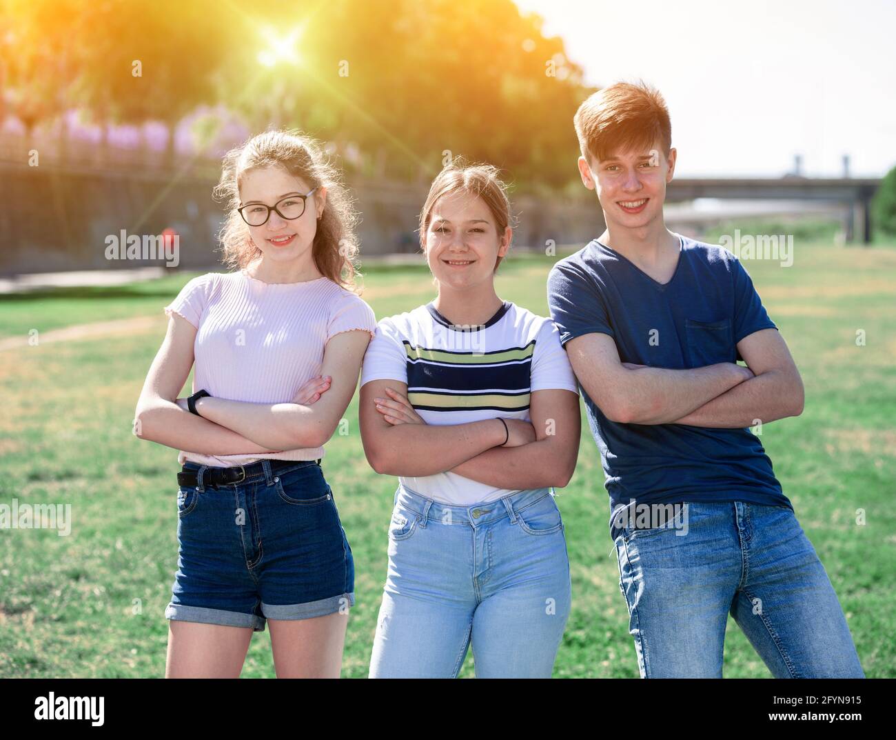 Portrait of three happy confident teenagers in city park on sunny ...