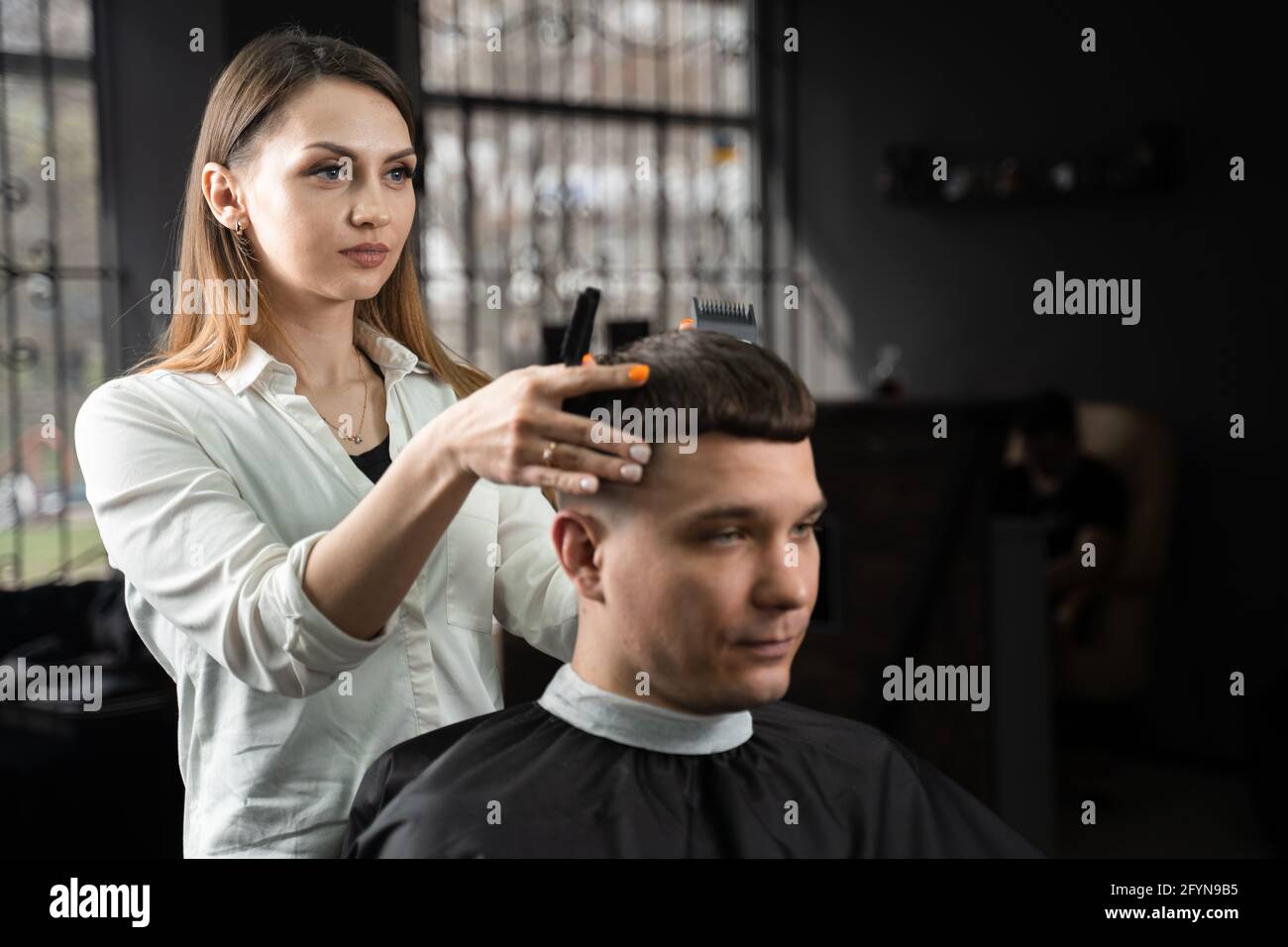 Woman barber making hairstyle in barbershop using clipper. Hairdresser ...