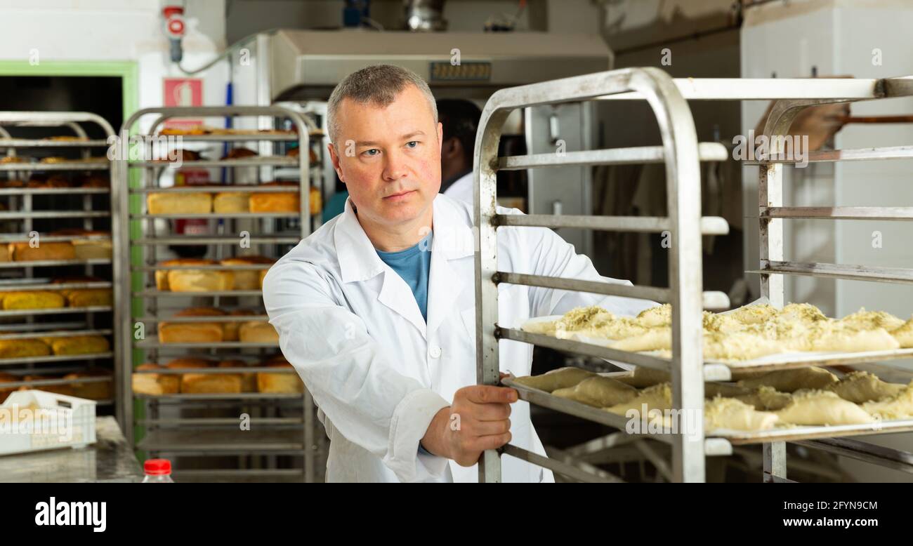 Baker pushing trolley with baked bread Stock Photo - Alamy
