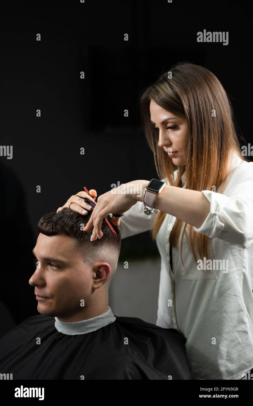 Haircut and styling in barbershop for handsome man. Woman making ...