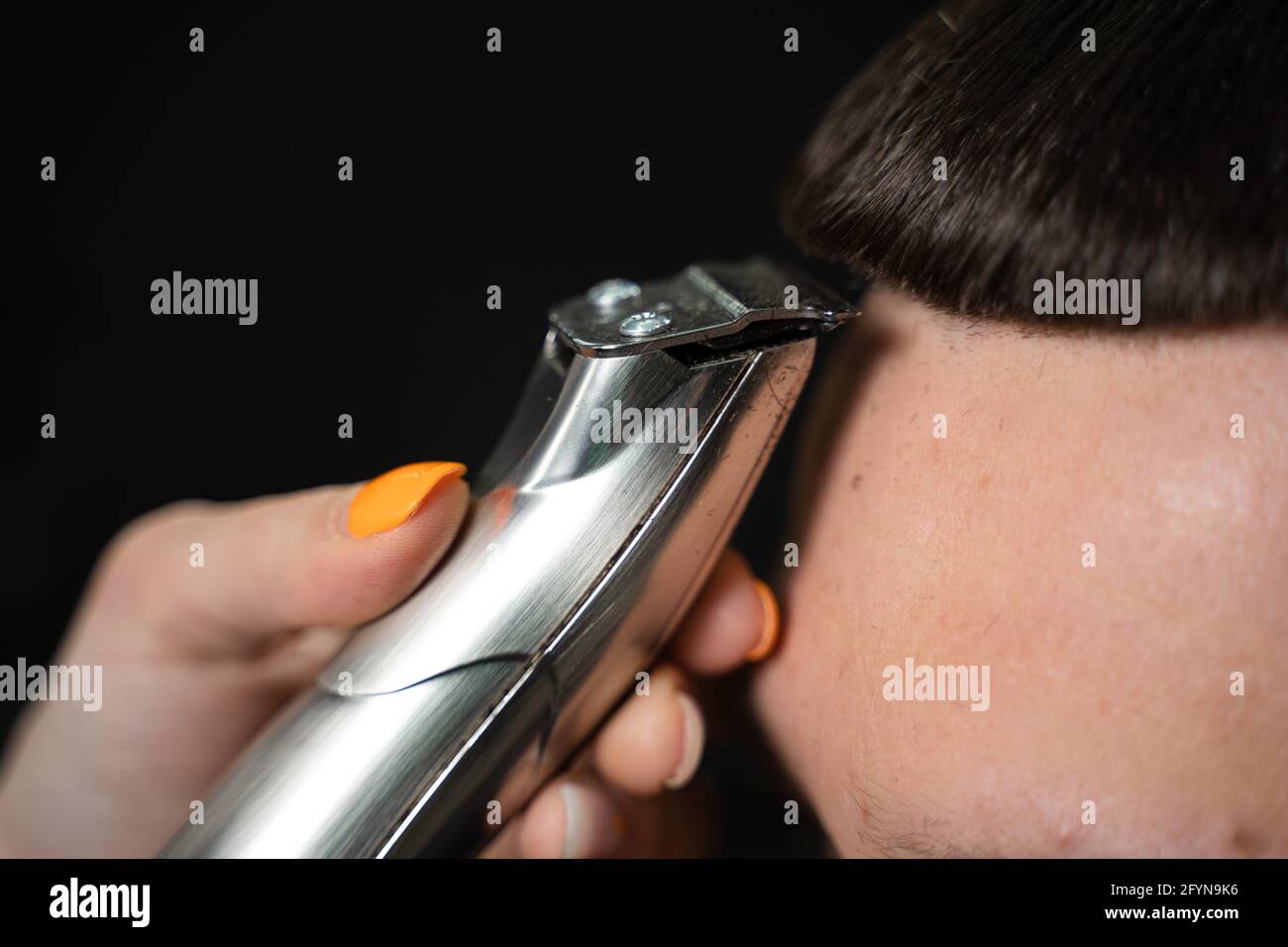 Trimming bangs of handsome man in barbershop. Woman hairdresser making ...
