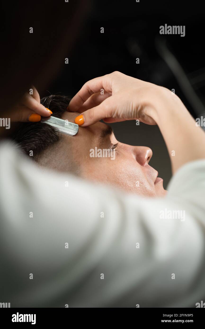 Straight razor cut man hair in barbershop. Attractive woman barber ...