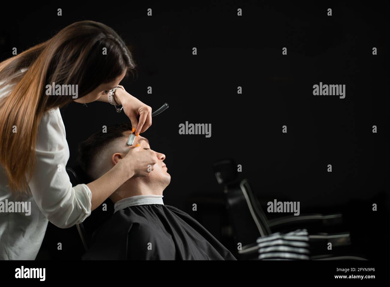 Straight razor cut man hair in barbershop. Attractive woman barber ...