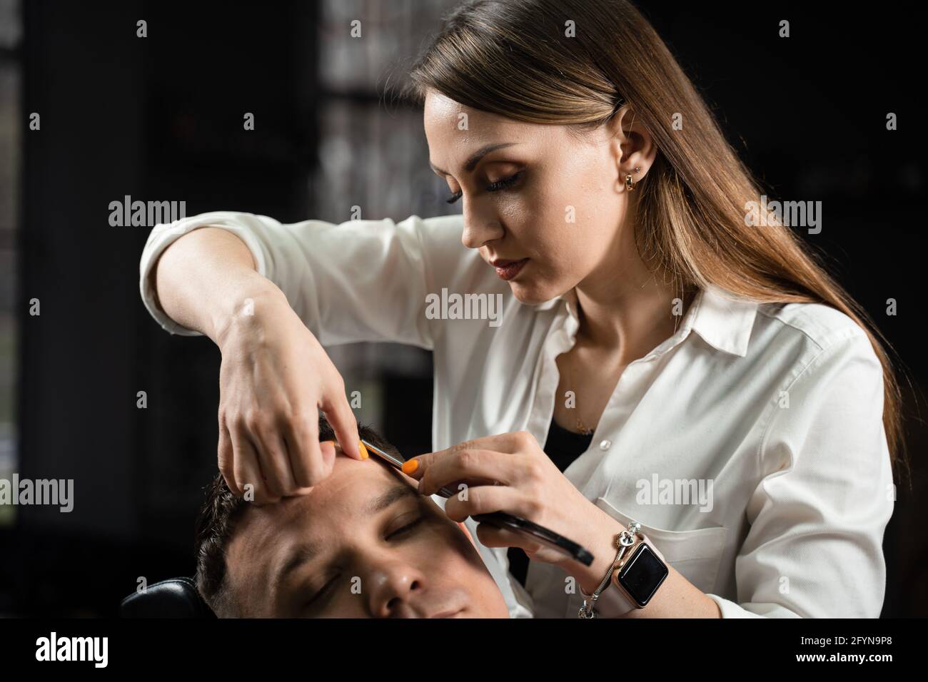 Straight razor cut man hair in barbershop. Attractive woman barber ...