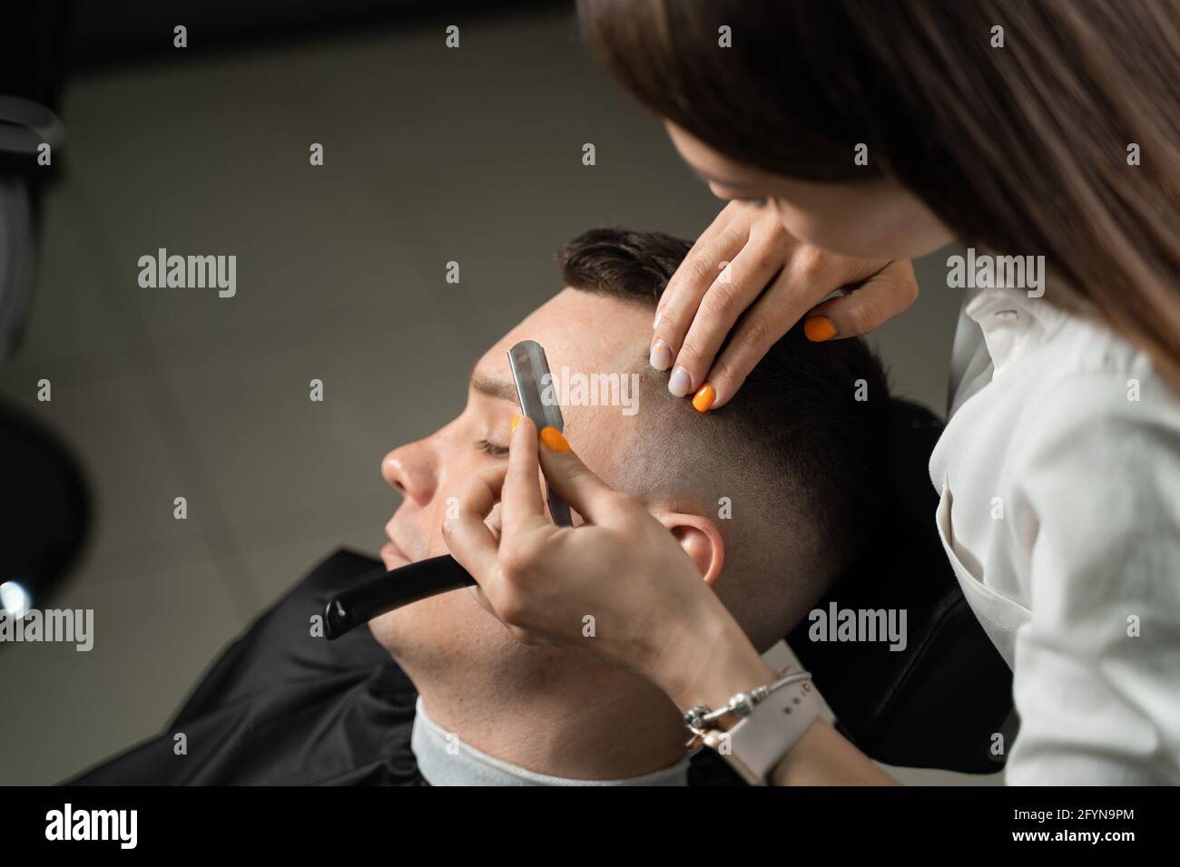 Straight razor cut man hair in barbershop. Attractive woman barber ...
