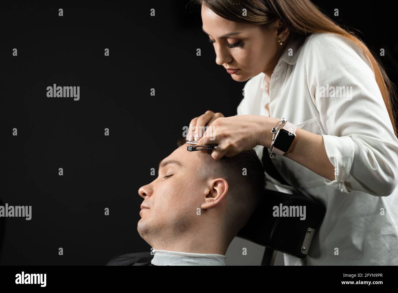 Straight razor cut man hair in barbershop. Attractive woman barber ...