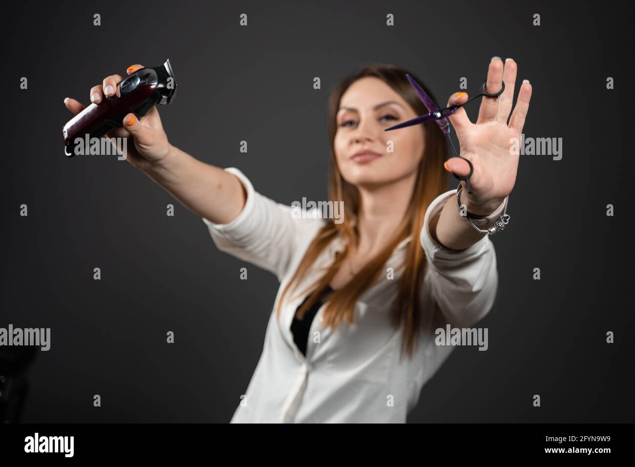 Woman barber with scissors and hair clipper in barbershop. Portrait of ...