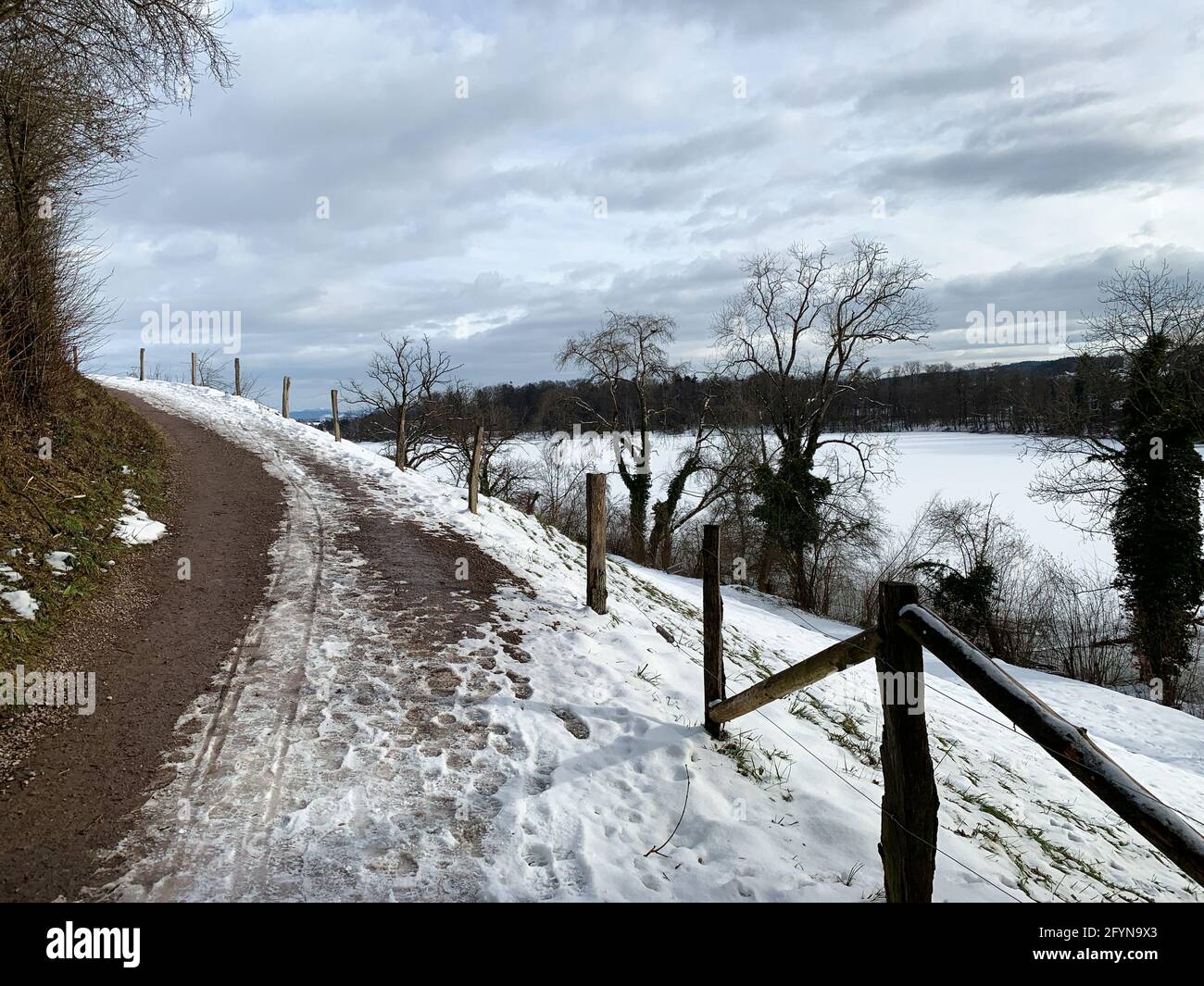 Hiking trail in the snowy landscape around the frozen lake Katzensee ...