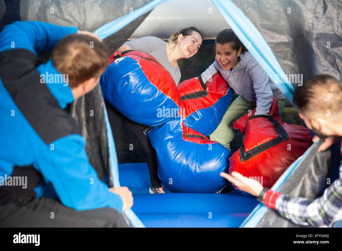 Happy female friends fighting by big stuffed boxing gloves at outdoor ...