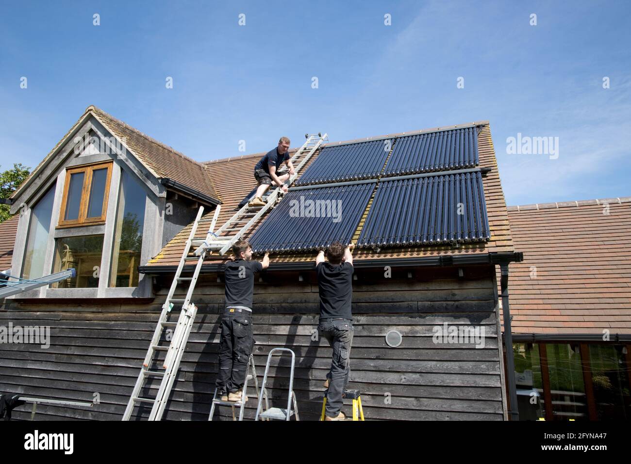 Heating engineer installing evacuated solar thermal collecting tubes on ...