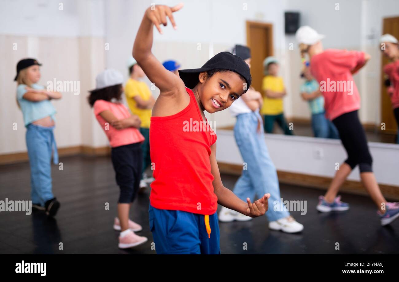 Portrait of emotional african boy doing hip hop movements during group ...