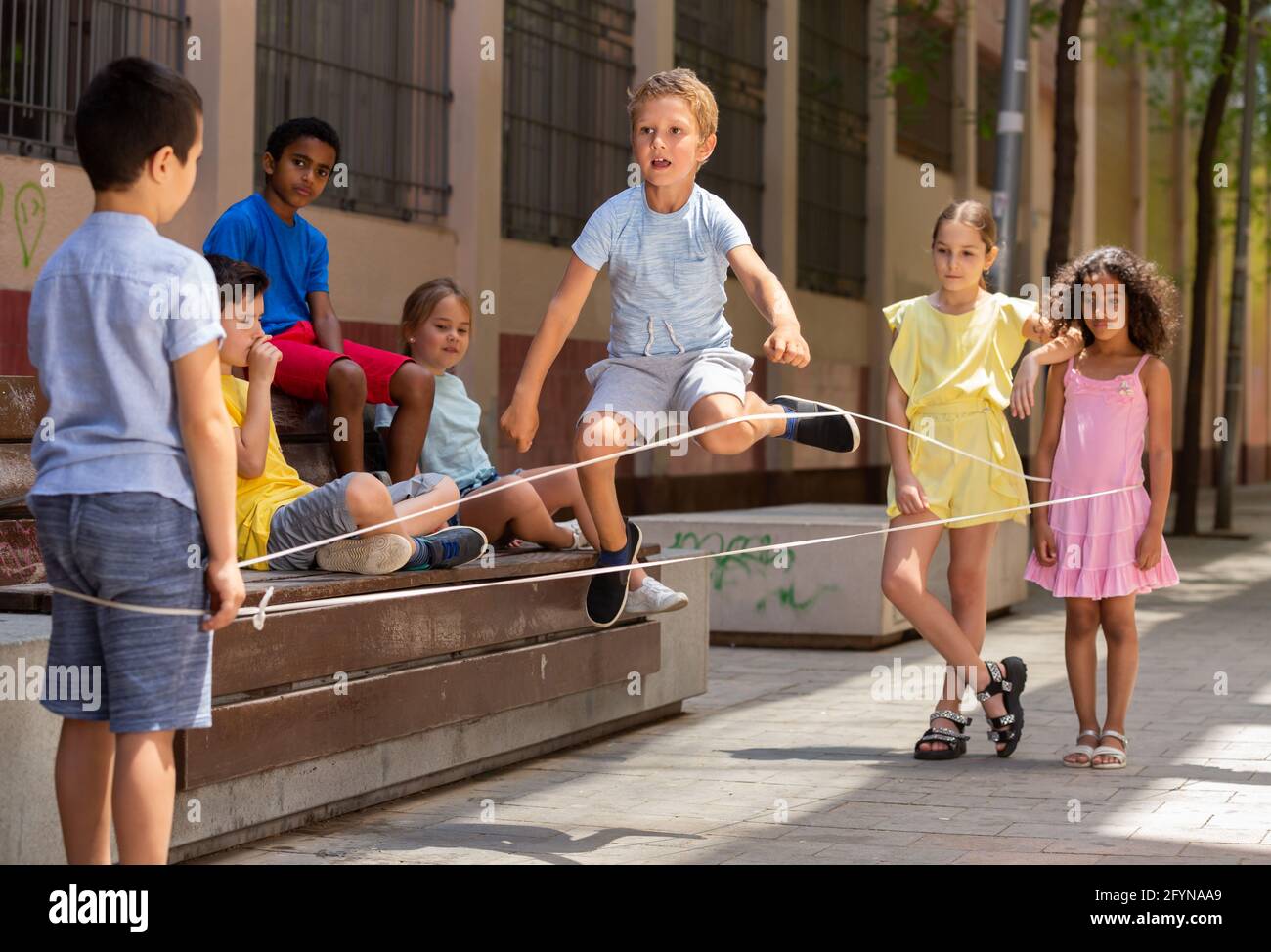 Happy smiling little friends playing with chinese jumping rope at ...