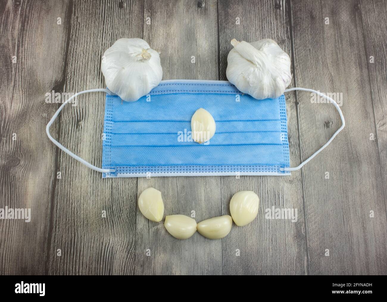 A face made of two cloves of garlic and peeled heads of garlic and a ...