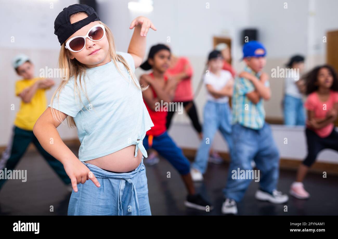 Portrait of emotional girl doing hip hop movements during group class ...