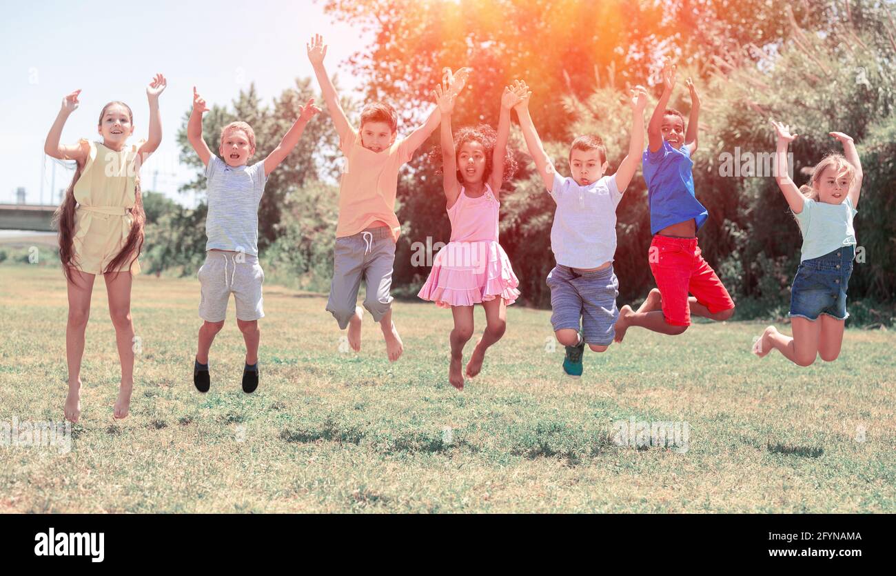 Friendly happy kids jumping together in park on summer Stock Photo - Alamy