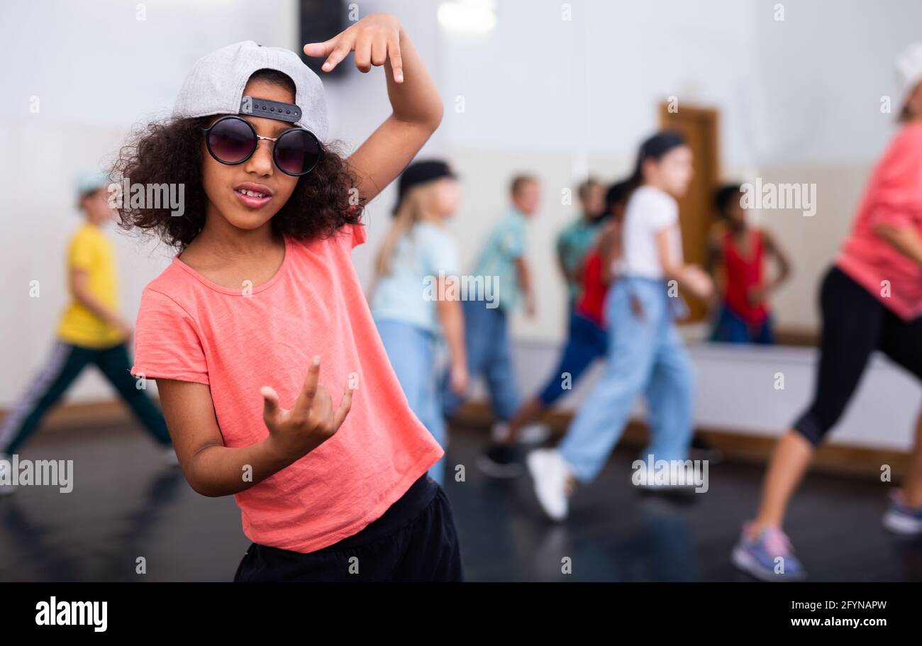Portrait of emotional african girl doing hip hop movements during group ...
