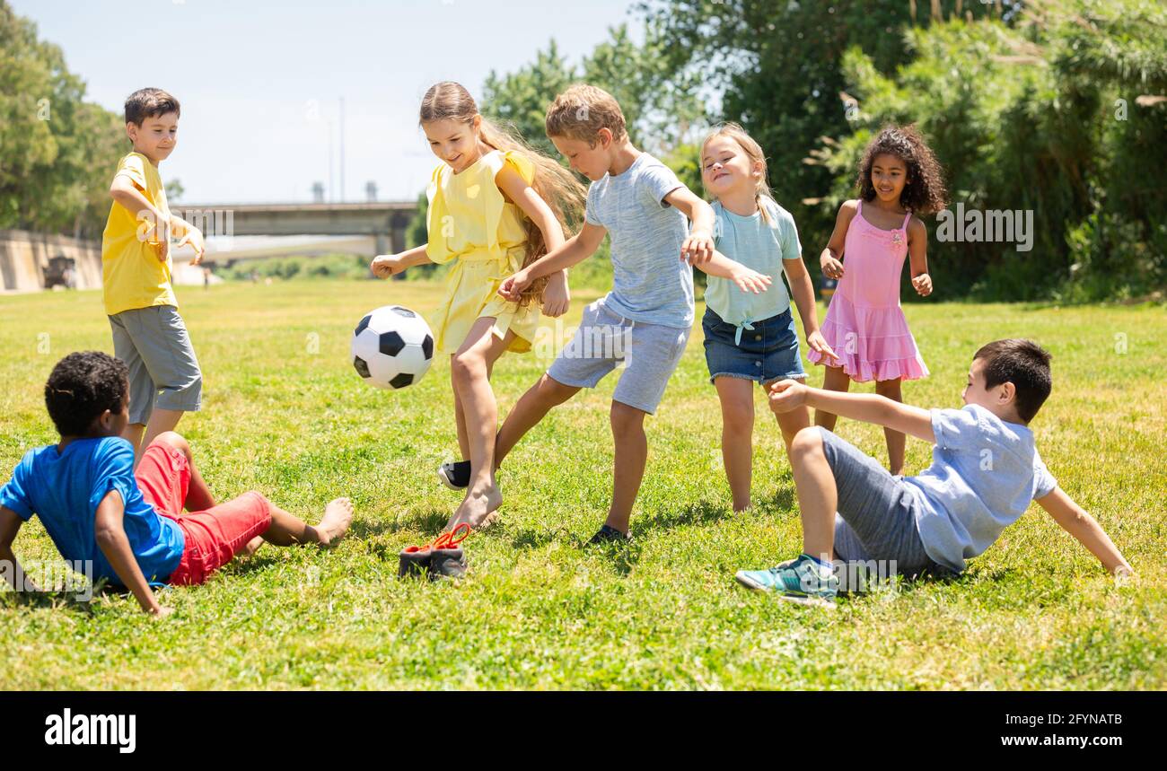 Group of happy schoolchildren playing football together in park Stock ...