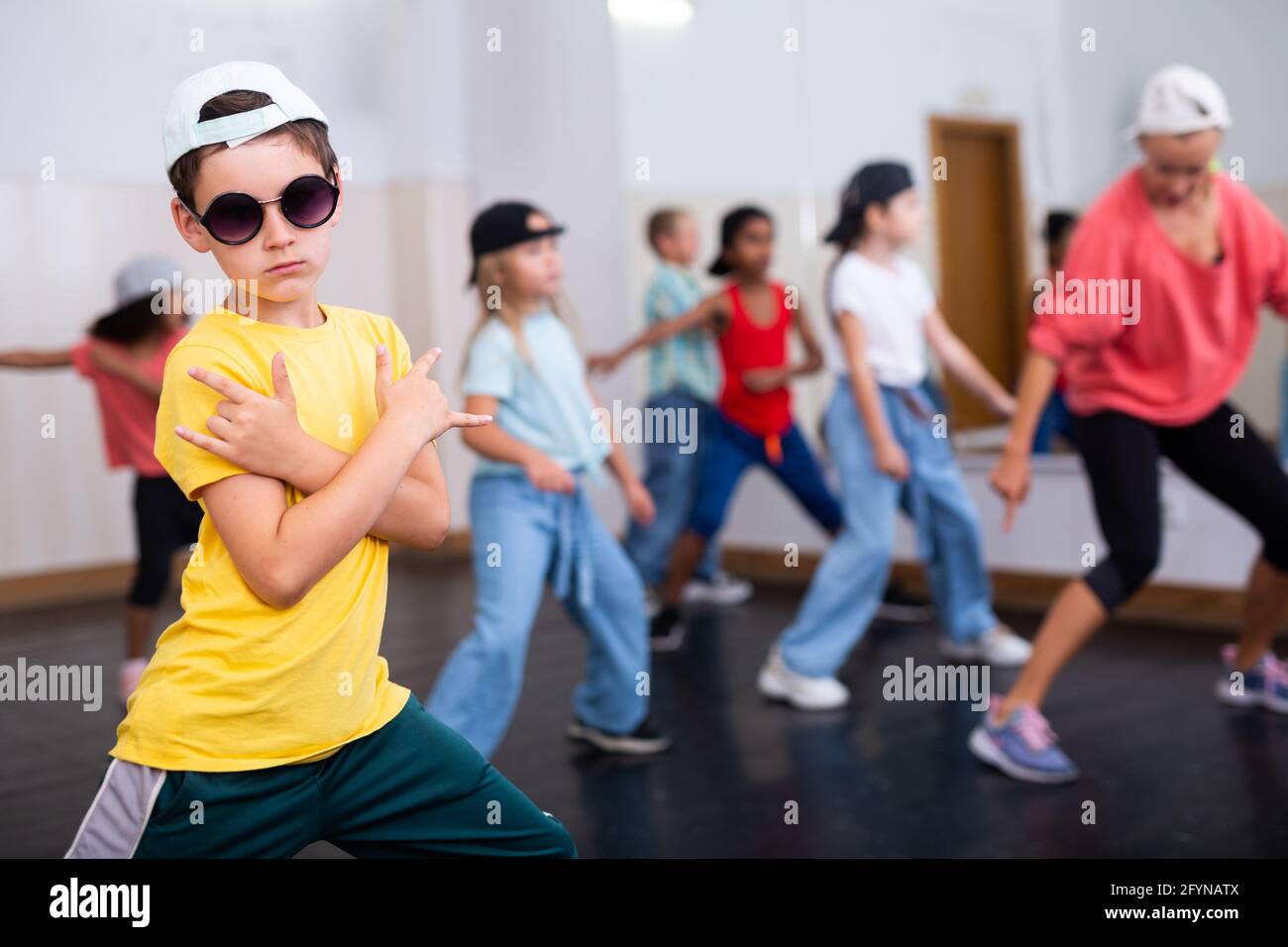 Portrait of emotional boy doing hip hop movements during group class in ...