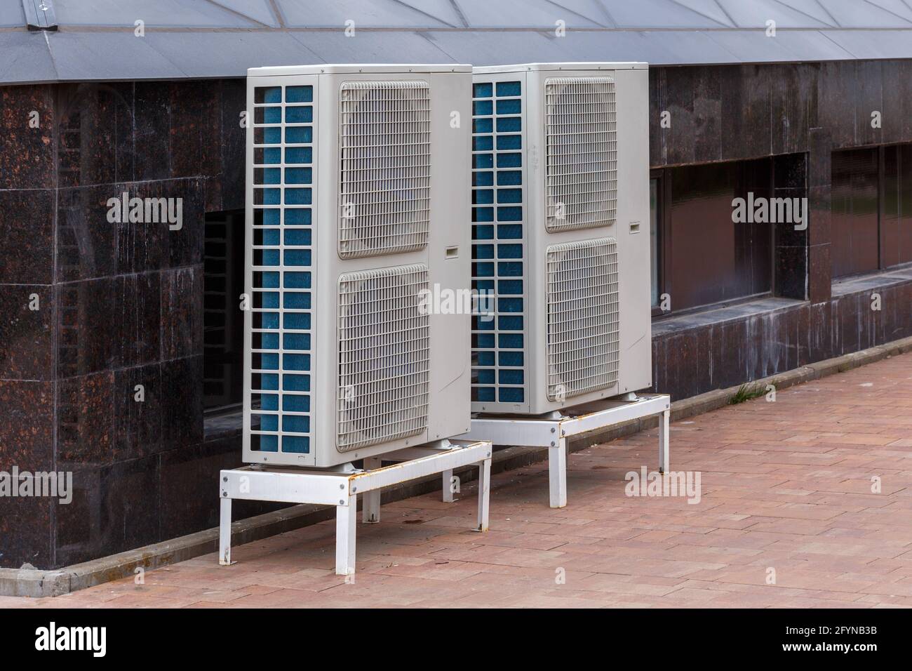 two double condensing units of air conditioner on the ground level near ...