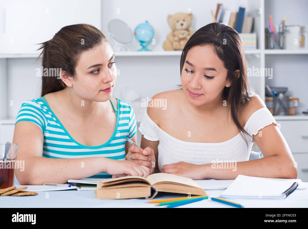 Teens girls studying together at home, doing homework and discussing ...