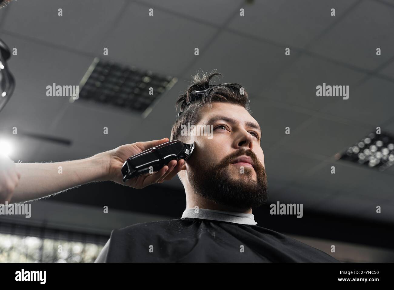 Low fade machine haircut for handsome bearded man in barbershop. Hair ...