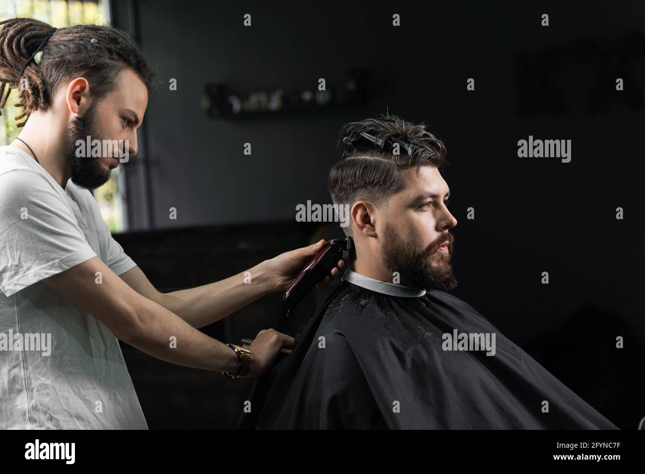 Low fade machine haircut for handsome bearded man in barbershop. Barber ...