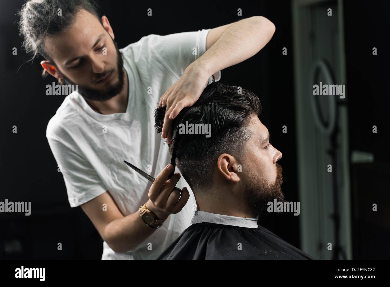 Low fade machine haircut for handsome bearded man in barbershop. Barber ...