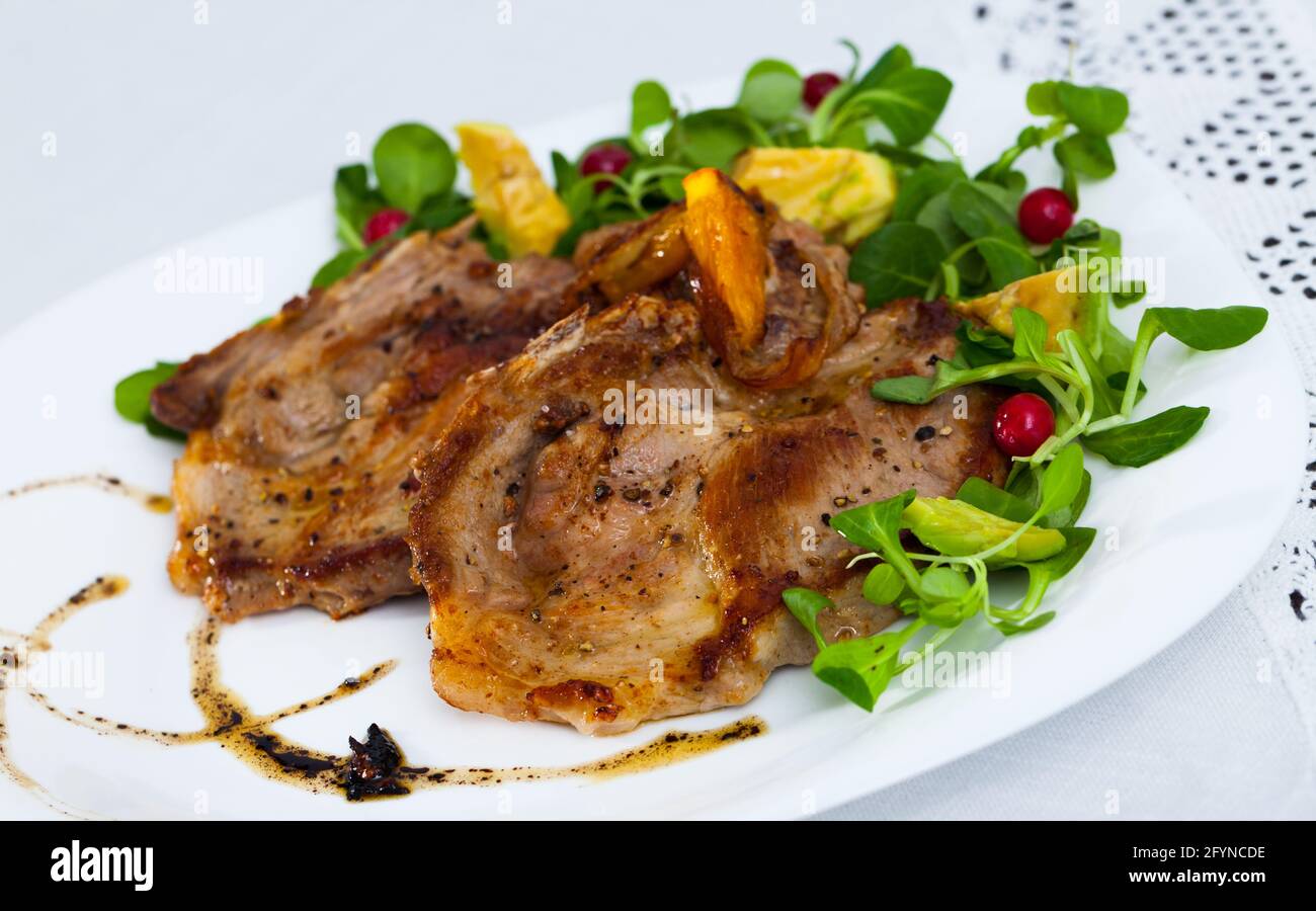 Grilled pork rib chop steak on white plate served with mash salad ...